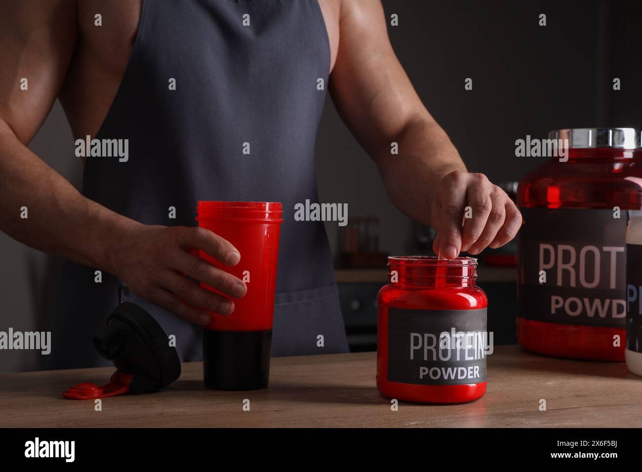 Handsome muscular man making protein shake with powder in kitchen ...
