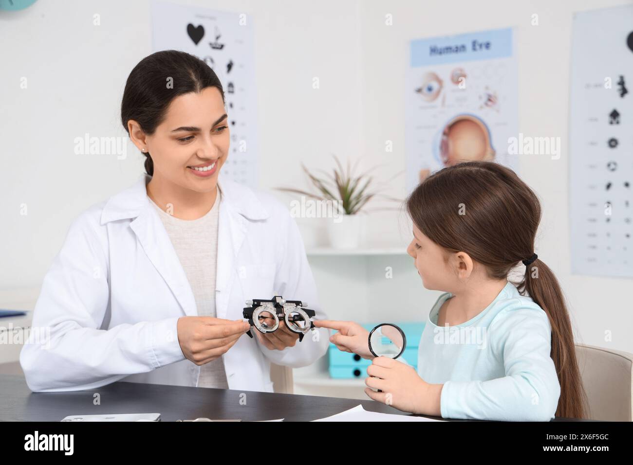 Female ophthalmologist with trial frame and little girl in clinic Stock ...