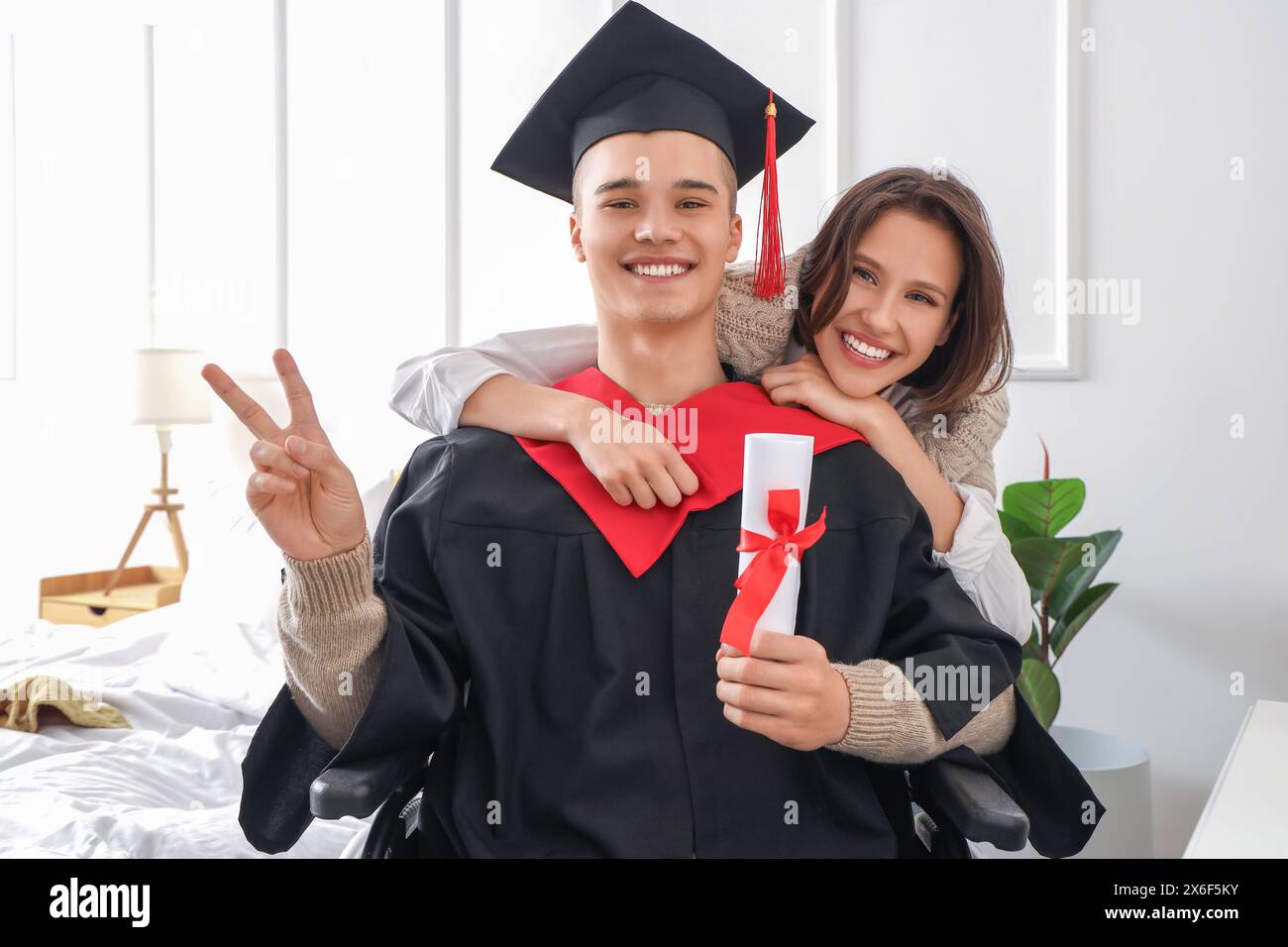 Male graduate in wheelchair with diploma showing victory gesture and ...