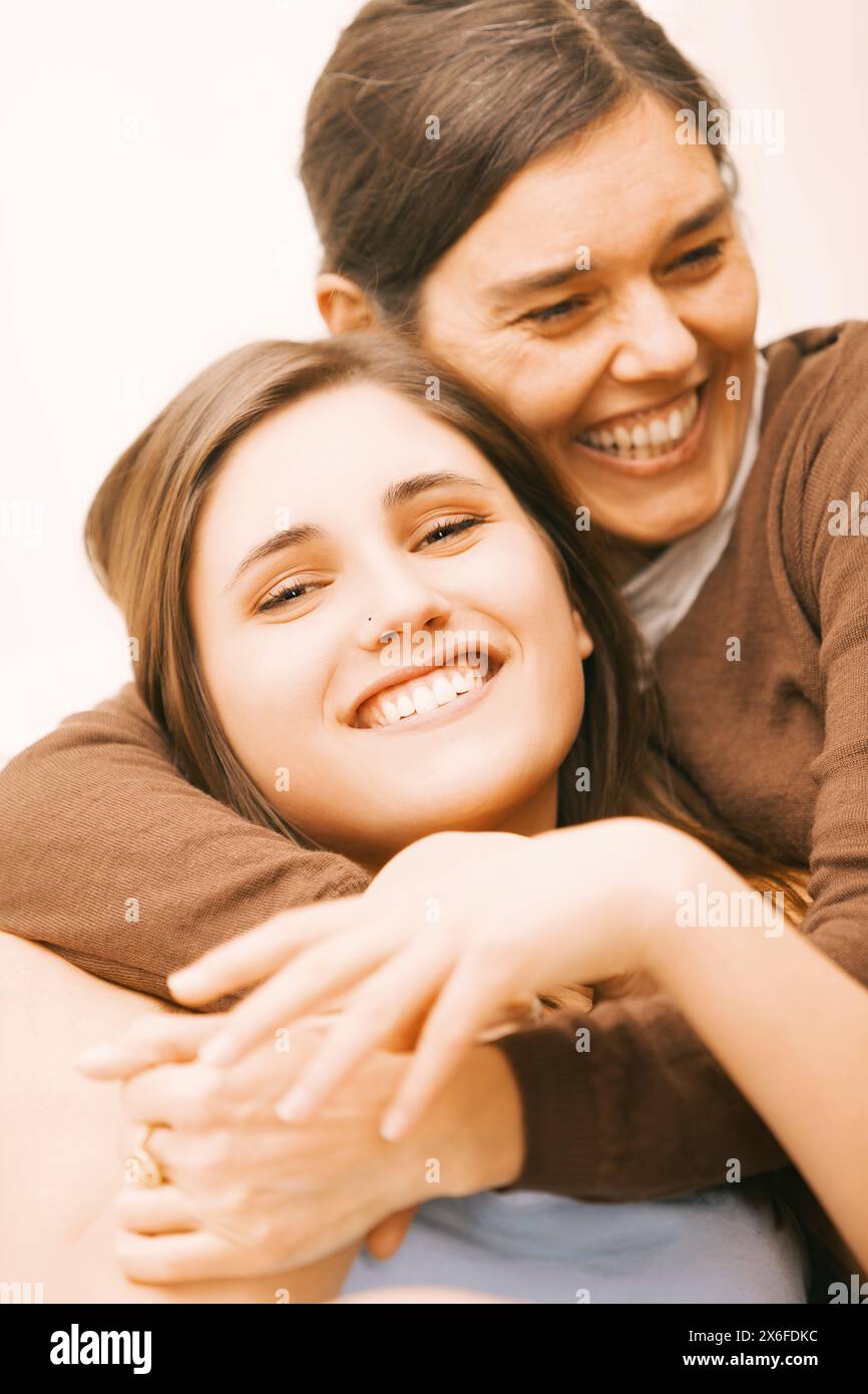 Middle-aged woman with a smile embraces young adult daughter lying on ...