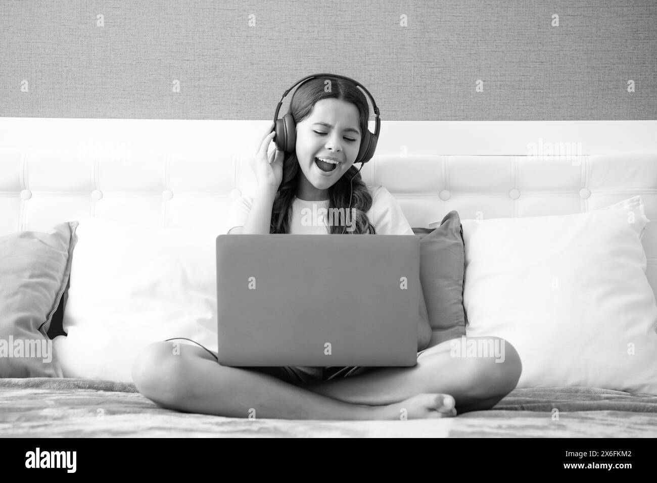 Happy teen teenage girl in headphones relax on bed at home listen to ...