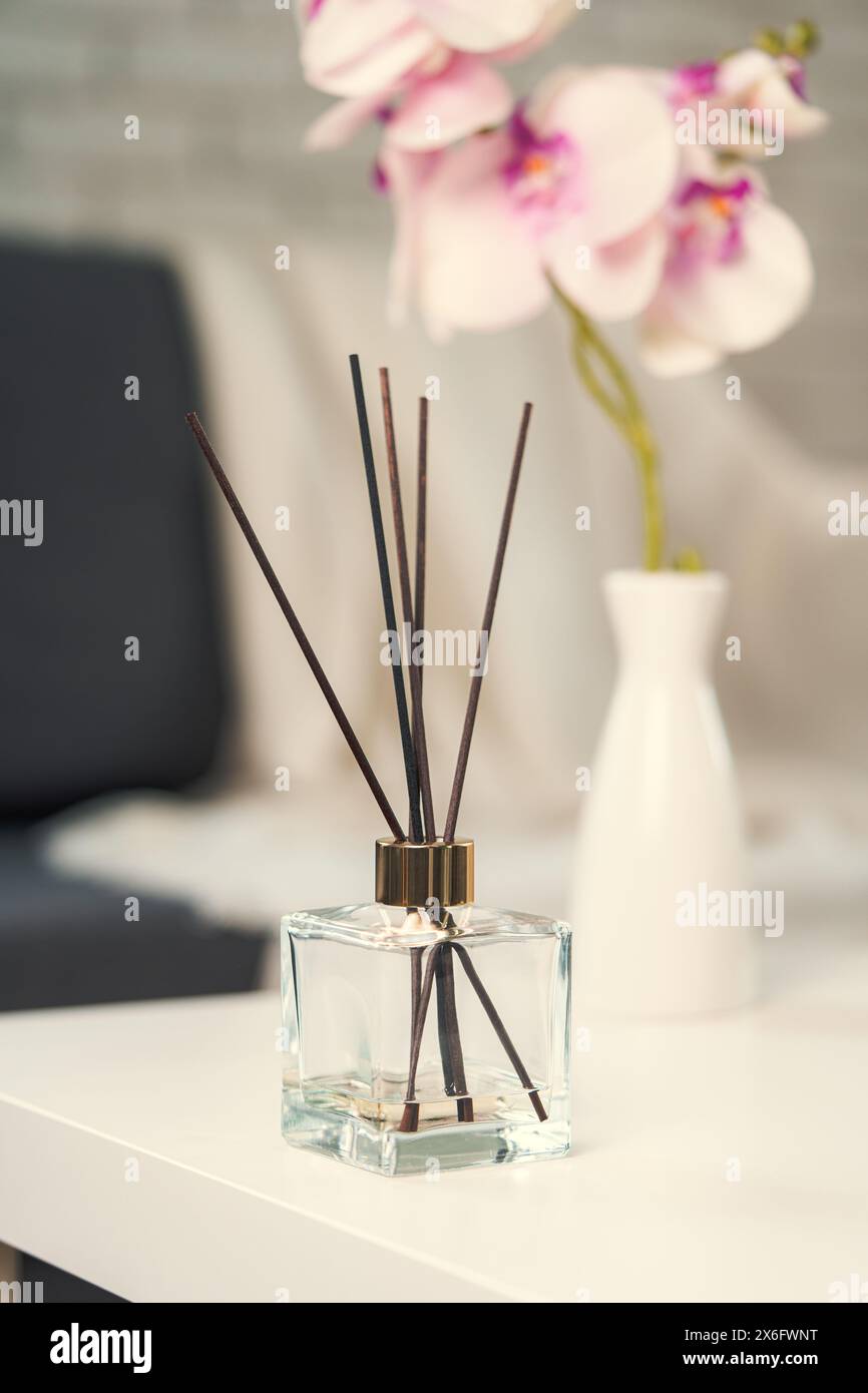 Liquid home perfume in glass diffuser with sticks on chair Stock Photo ...