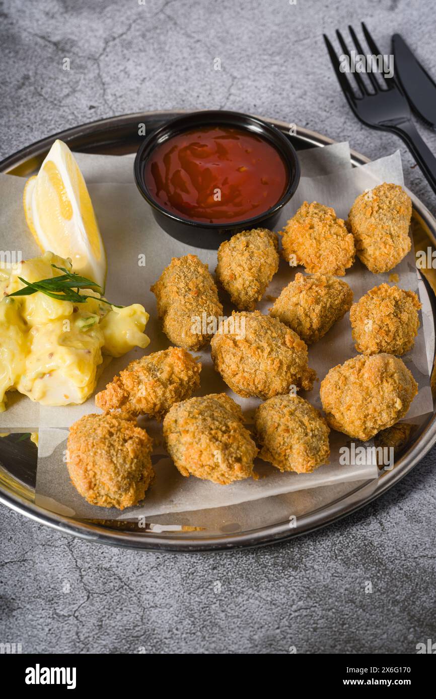 Fried mussels on a metal plate with potato salad on the side. Turkish ...