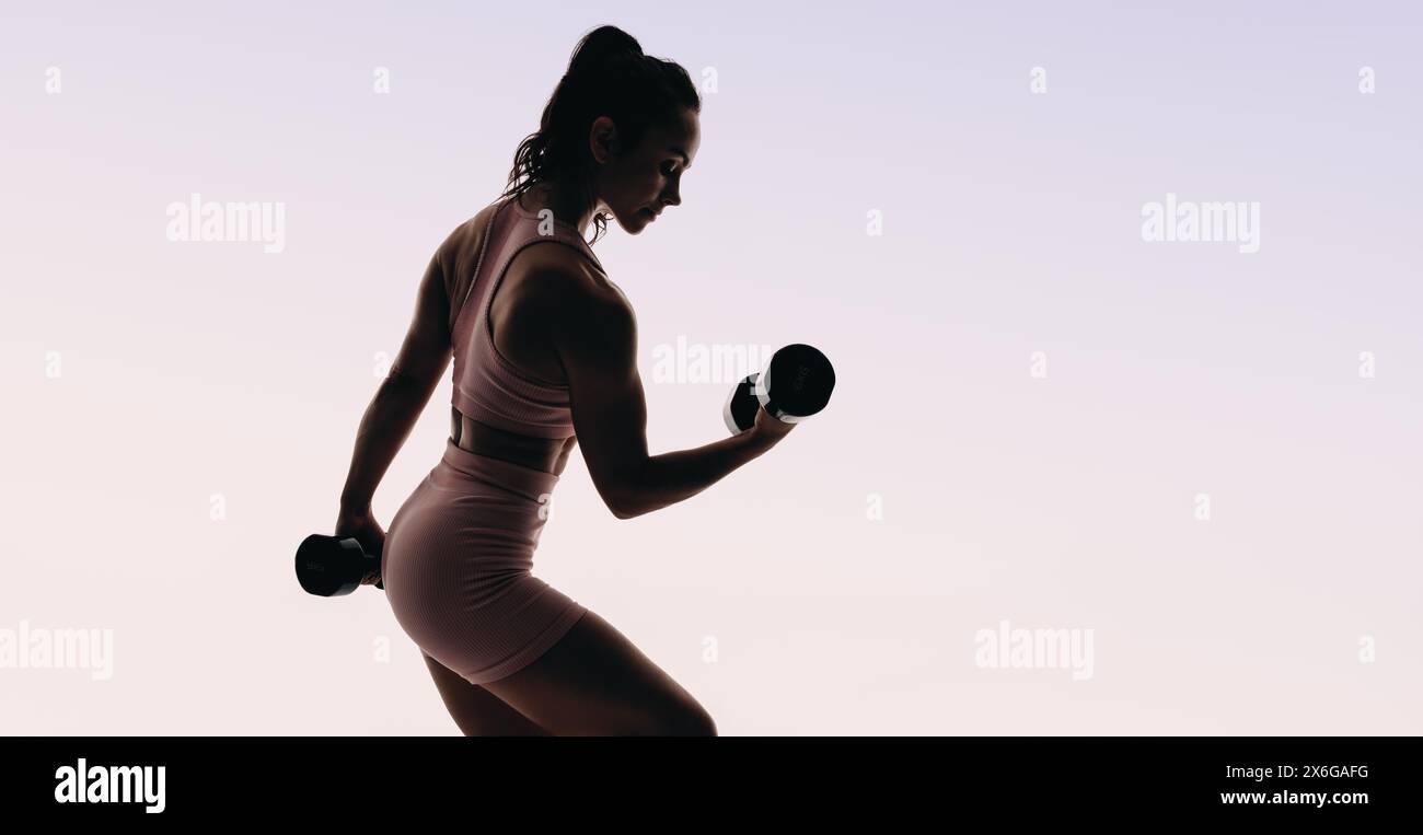 Woman in fitness clothing engages in weight training and bodybuilding ...