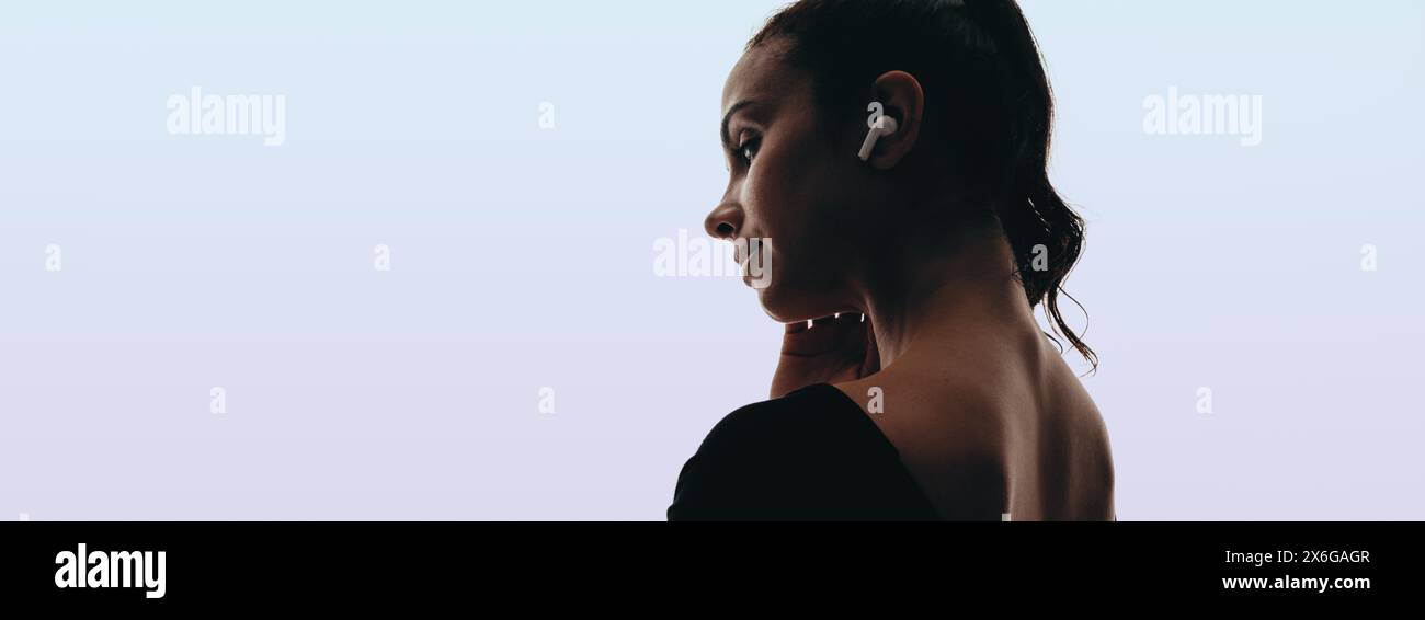 Woman with a ponytail hairstyle stands in a studio setting, using ...
