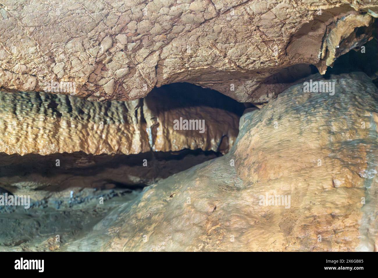 A cave with a brown wall and a small hole in it. The cave is dark and ...