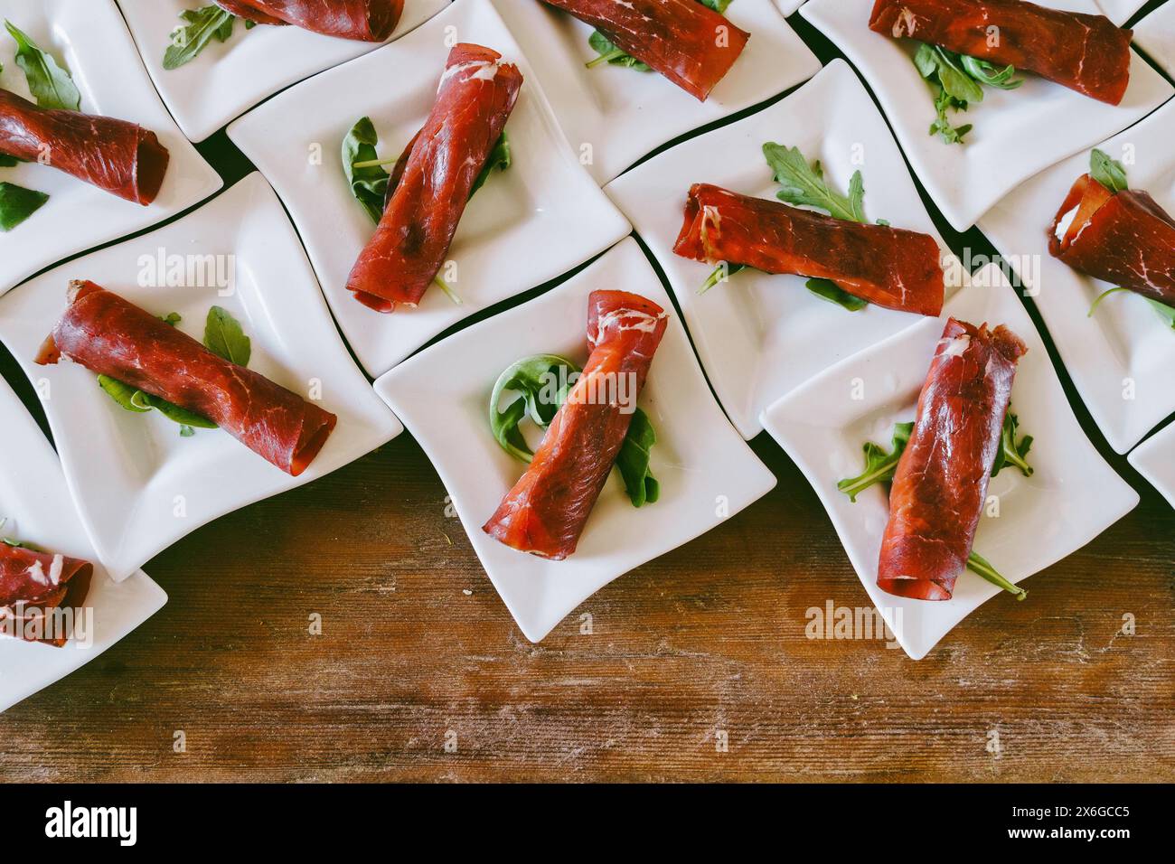 Elegant presentation of meat appetizers on a bed of greens, arranged in ...