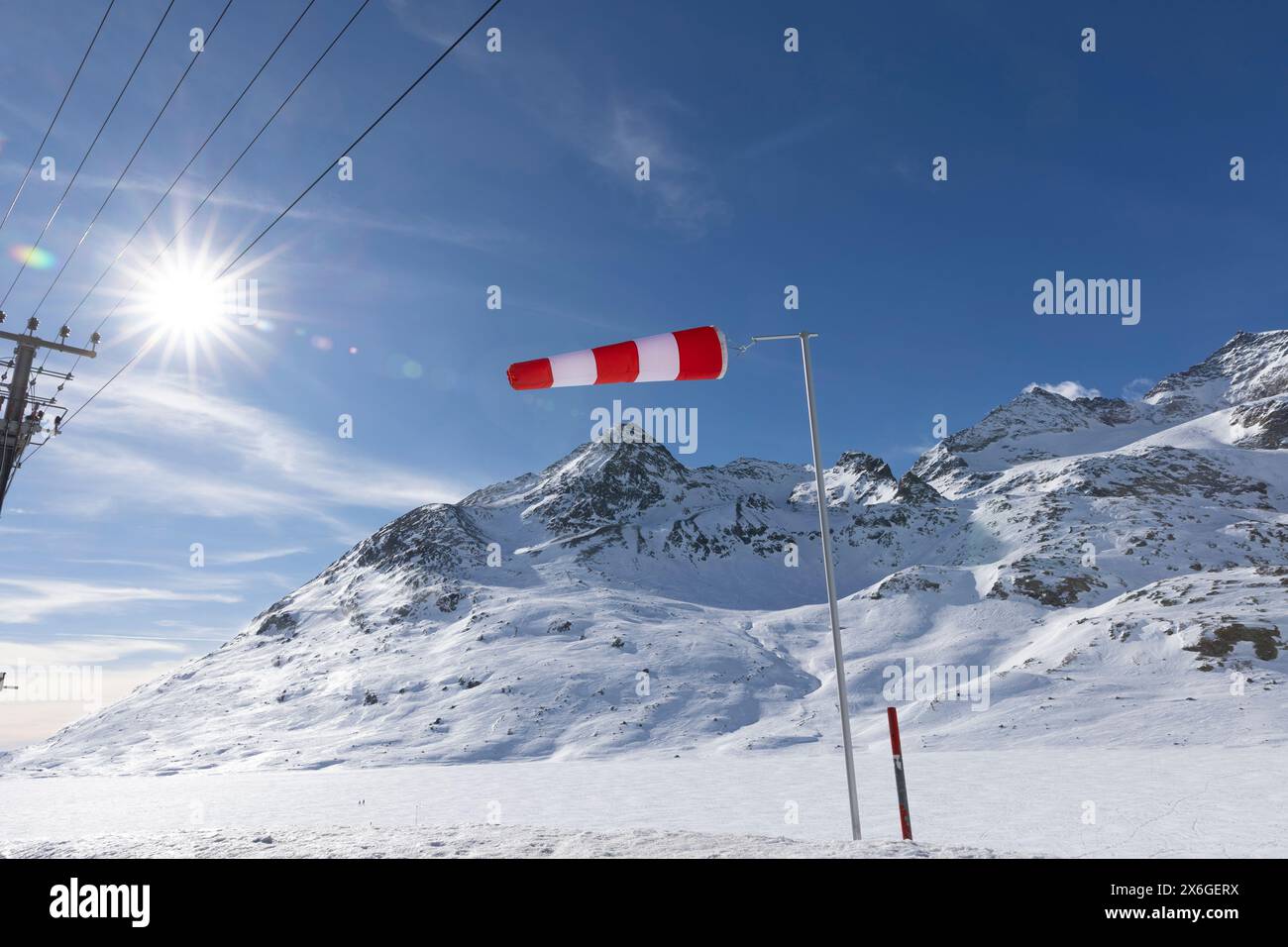 Detail of a white and red windsock on a blanket of snow. Behind the ...