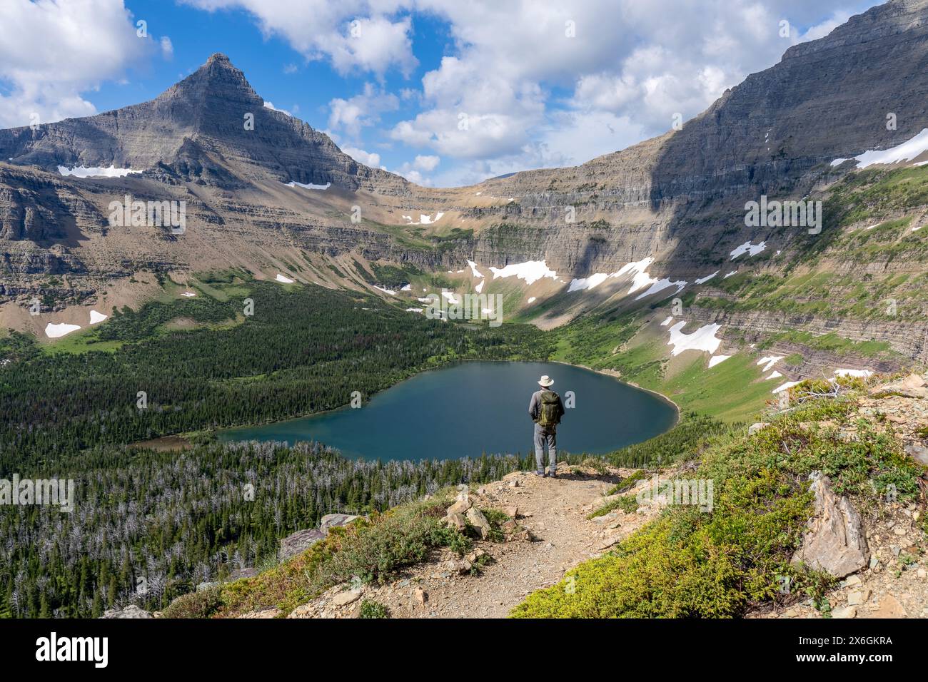 Matured Caucasian man standing looking a valley with a lake surrounded ...