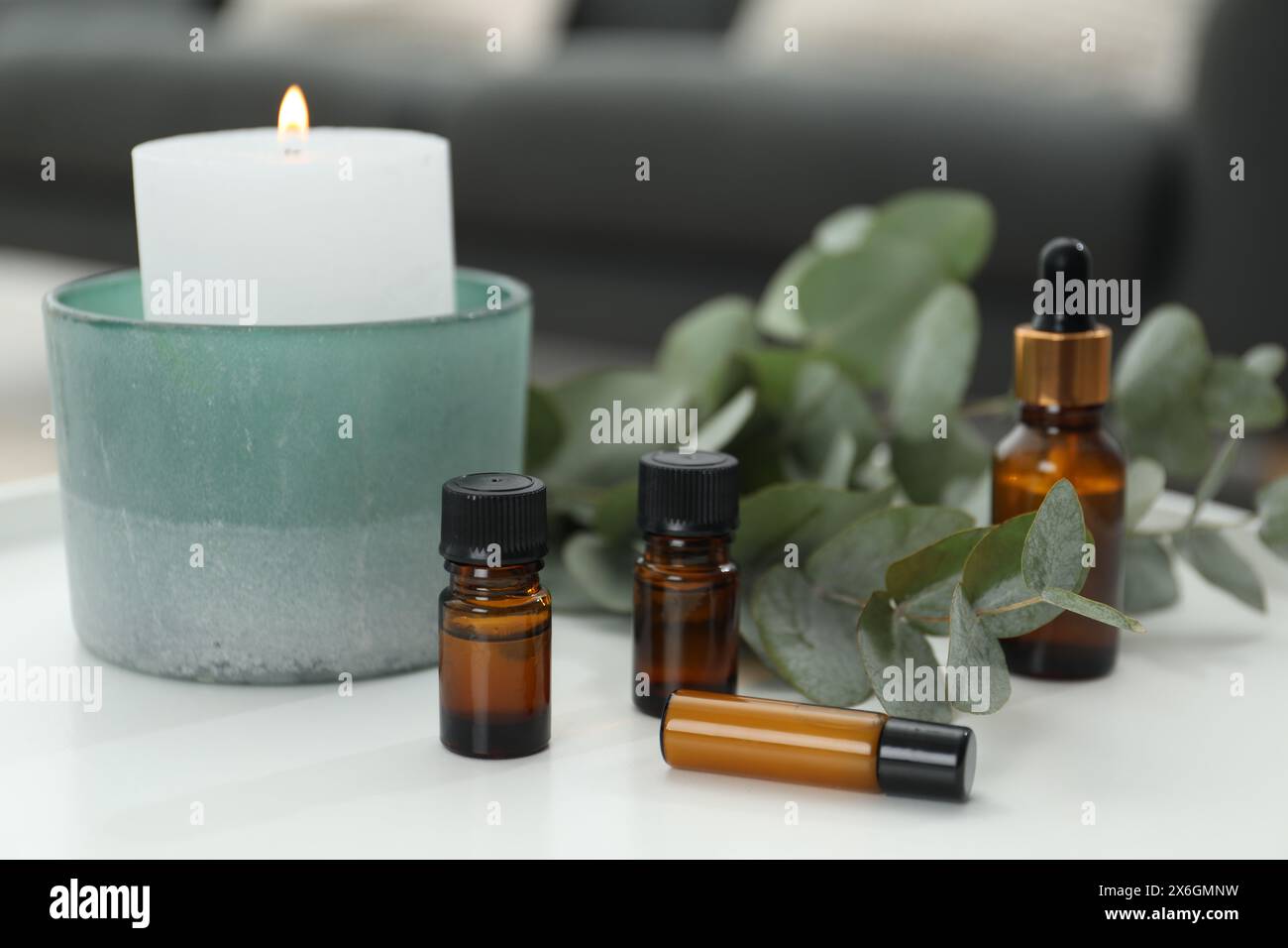 Aromatherapy. Bottles of essential oil, burning candle and eucalyptus ...