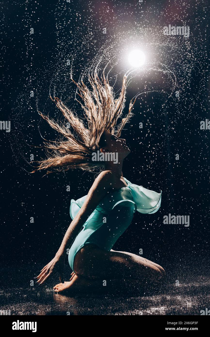 Ballerina teenager girl in green bodysuit dancing under falling water ...