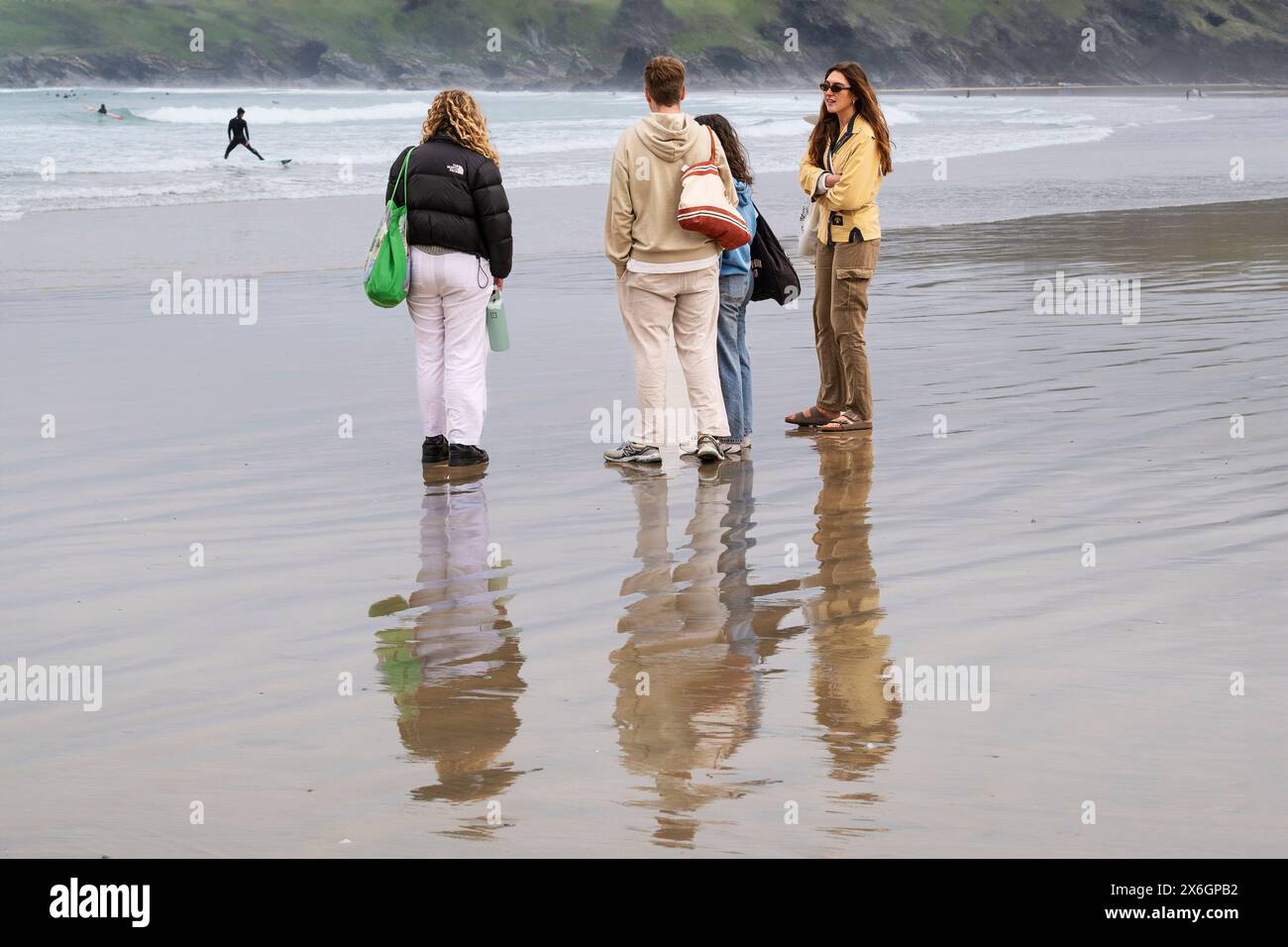 A group of young holidaymakers visitors tourists standing at low tide ...