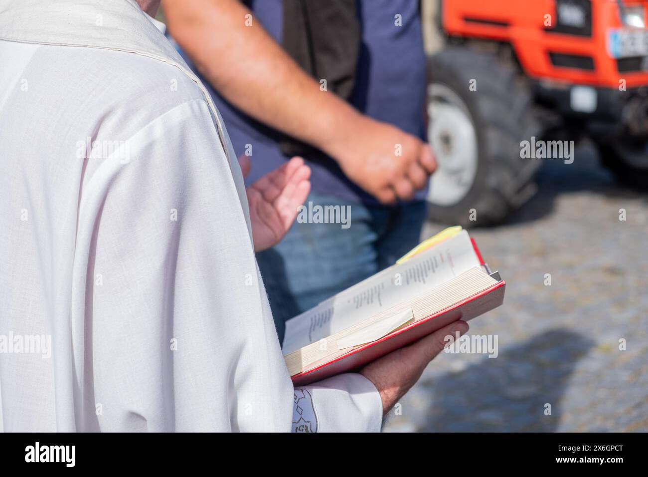 catholic priest holding a bible while celebrating an outdoor service ...
