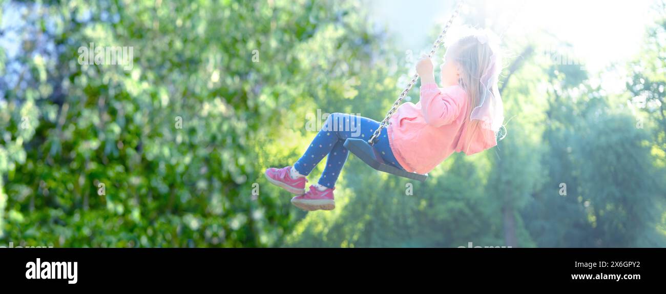 joyful little girl ascends into sunny sky on swing, blurred child ...