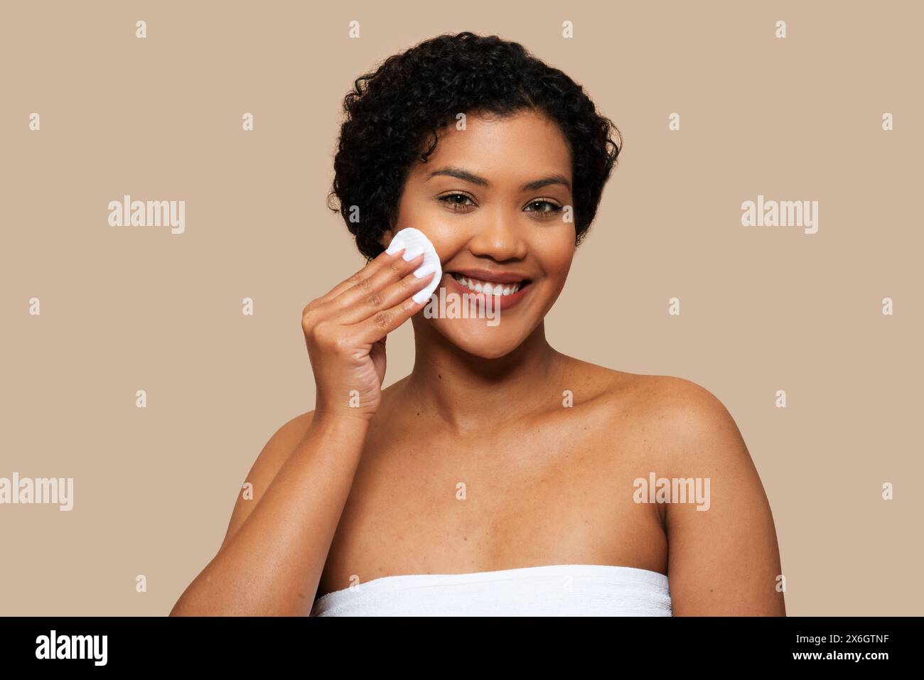 Radiant Young Woman Applying Facial Skincare Product Against Beige ...