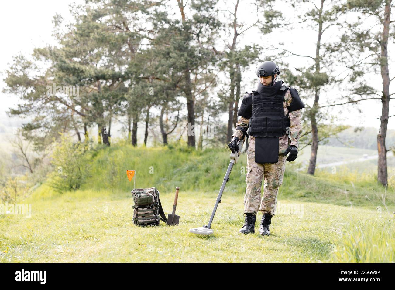 A man in a military uniform and bulletproof vest works in the forest ...