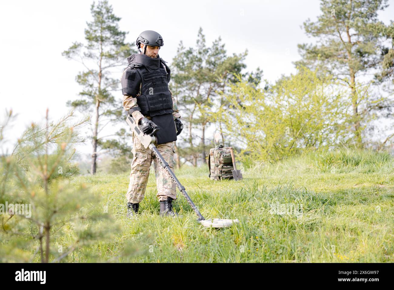 A man in a military uniform and bulletproof vest works in the forest ...
