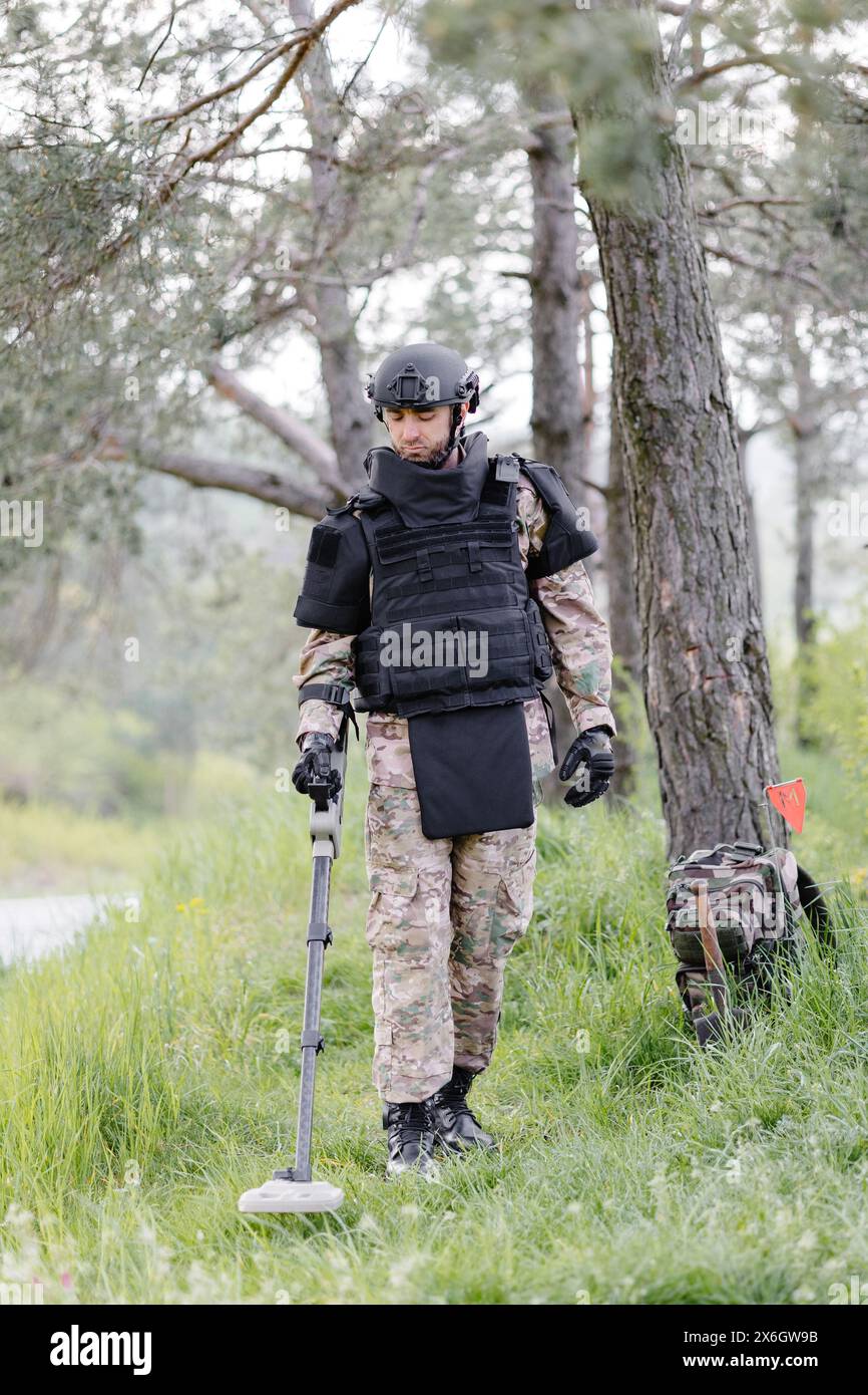 A man in a military uniform and bulletproof vest works in the forest ...