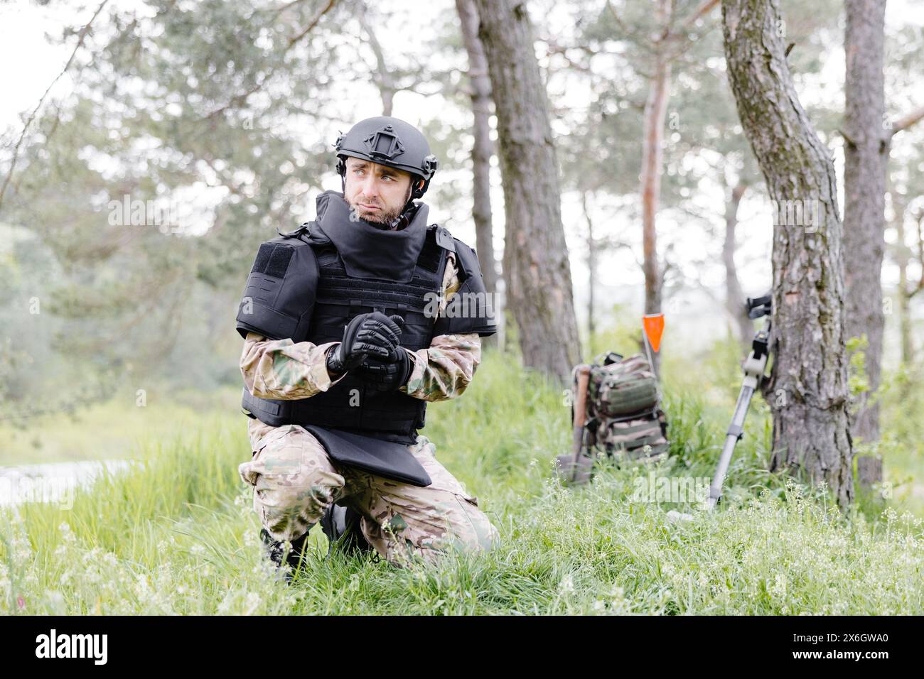 A man in a military uniform and a bulletproof vest works in the forest ...