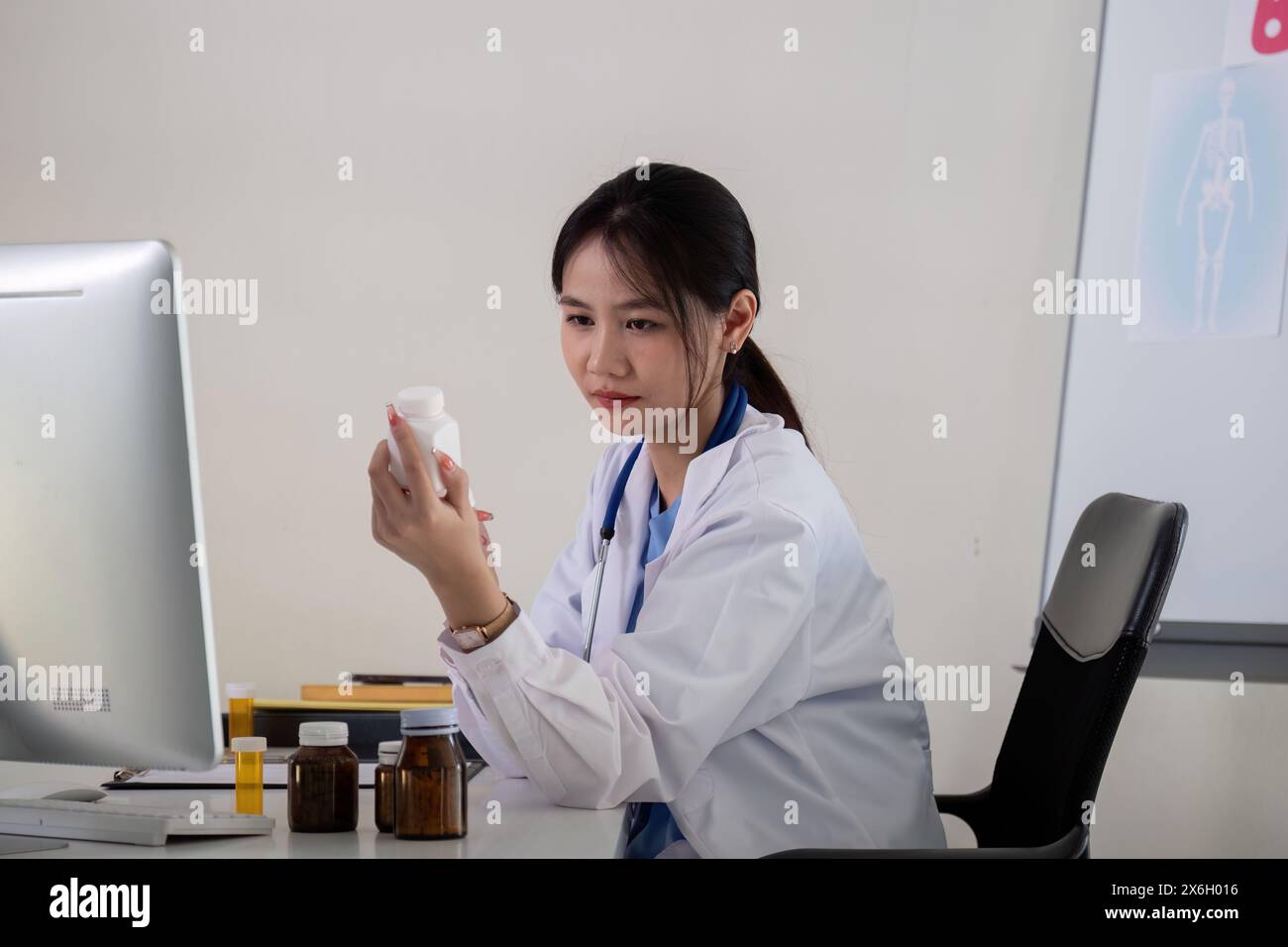 Asian Female Doctor Examining Medication Bottle in Medical Office Stock ...