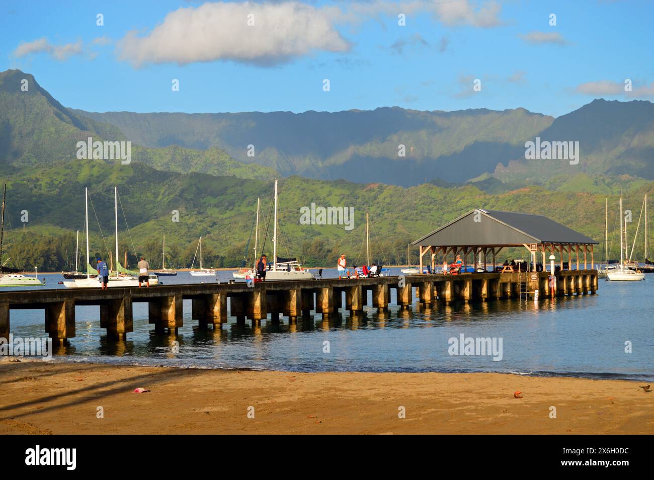 People enjoy walking on a pier in Hanalei Hawaii, on Kauai, and getting ...