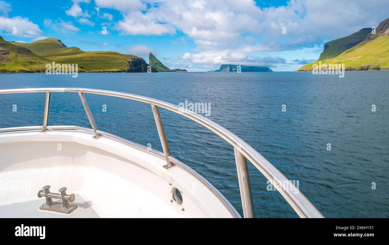 View of the tourist boat cruising at Faroe Islands fjords at blue sky ...