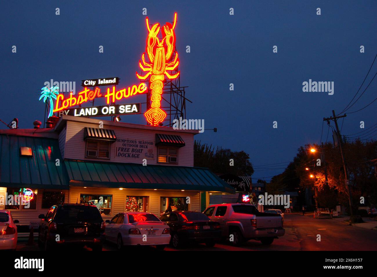 A large neon light sign is illuminated over a seafood restaurant and ...