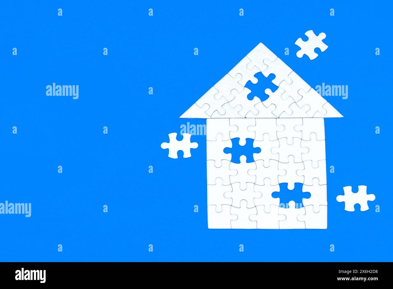 White hip roof house made up of interlocking jigsaw puzzle pieces set ...