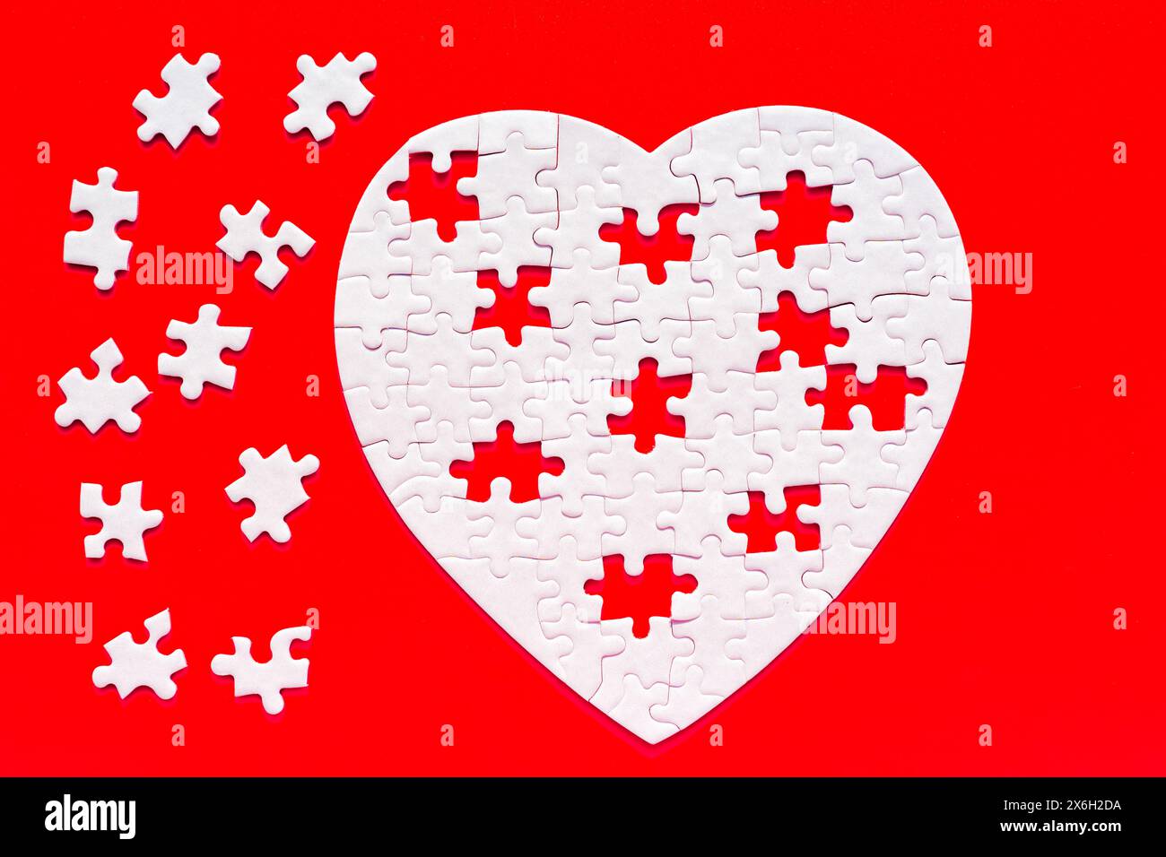 Incomplete heart-shaped puzzle set against a bold red backdrop. The ...