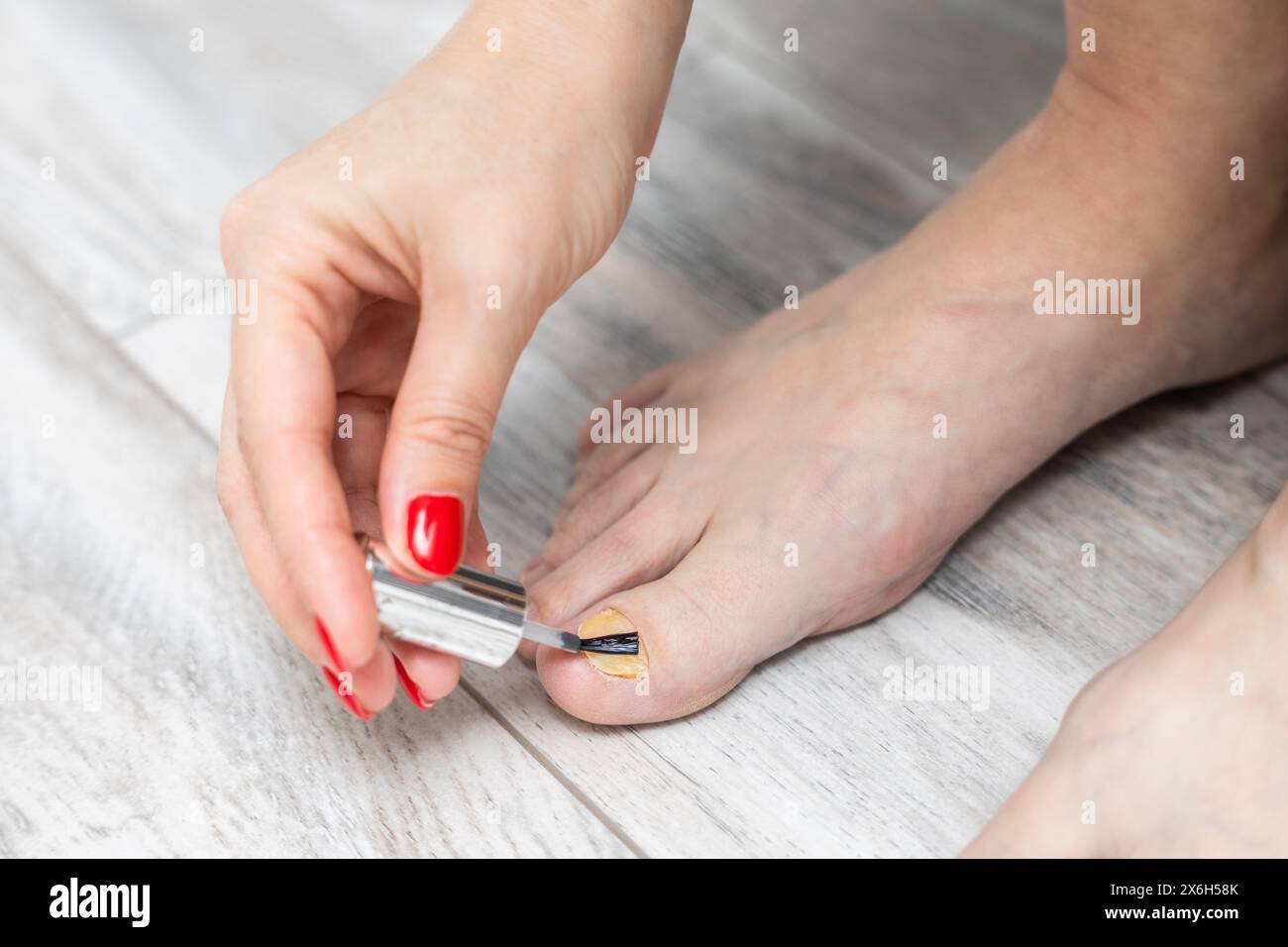 woman applying strengthening varnish to her big toe nail. applying ...