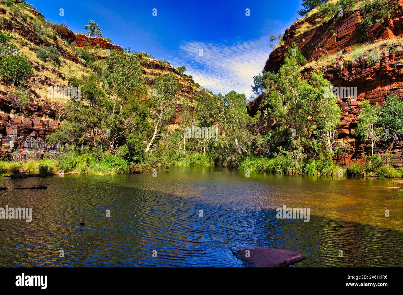 Cool pool, flanked by red, iron-rich rocks and green trees, a lush ...