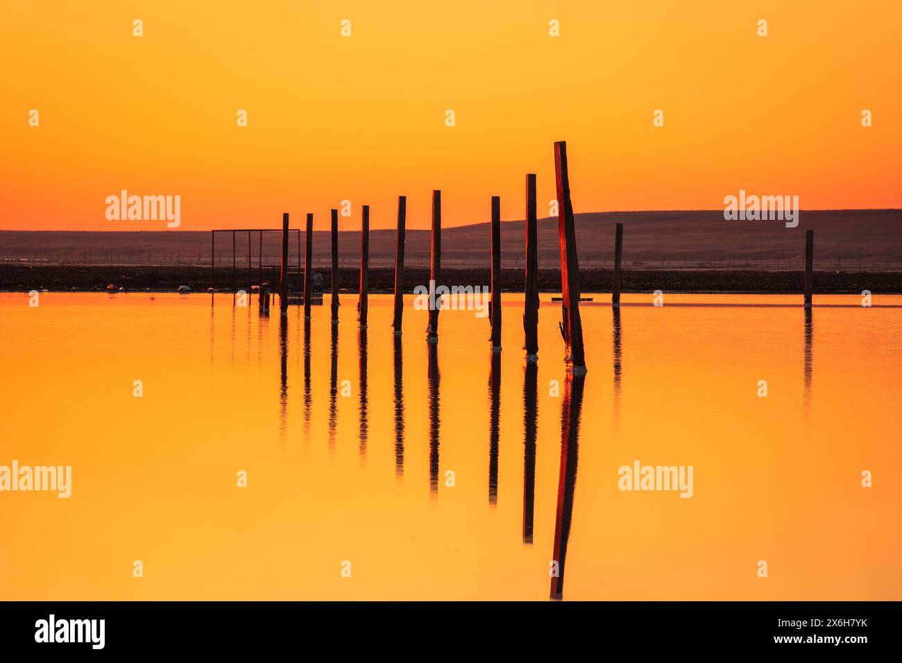View of a salt lake with pillars and reflection in the water at sunset ...