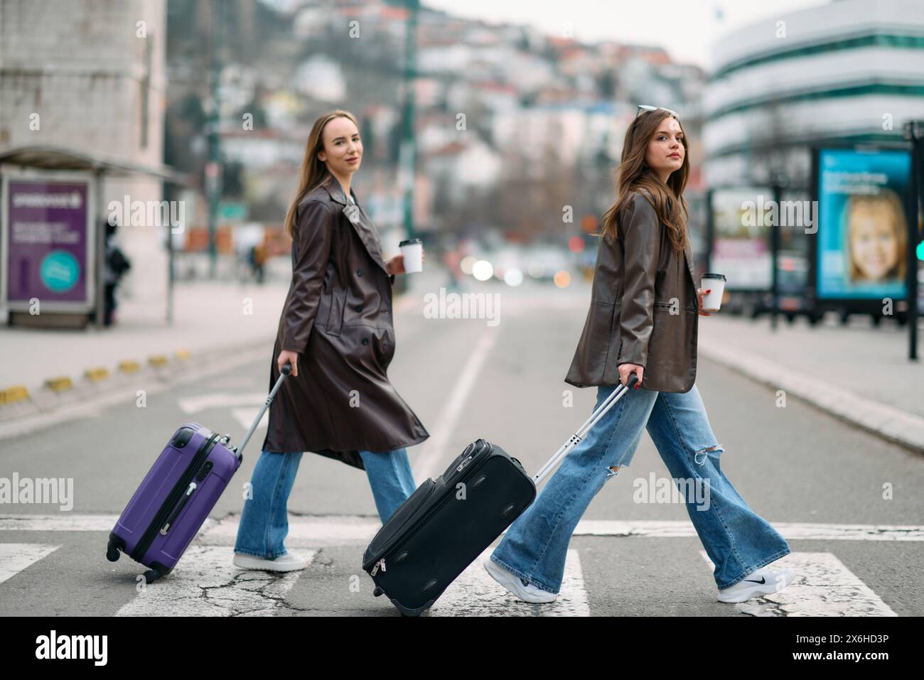 Two female tourists explore a European city, pulling their suitcases ...