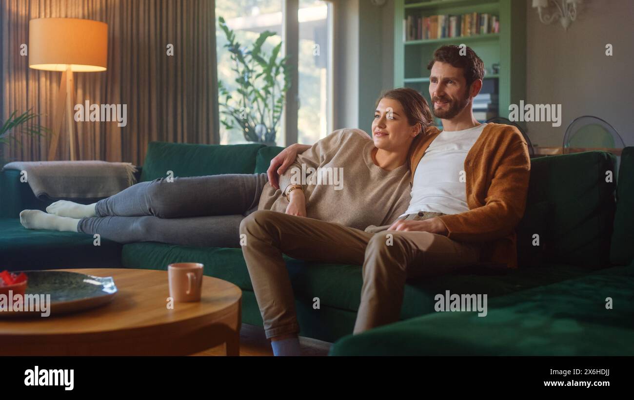 Couple Watches TV together while Sitting on a Couch in the Living Room ...