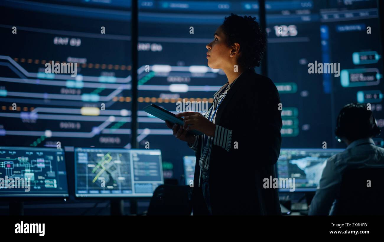 Young Multiethnic Female Government Employee Uses Tablet Computer in System Control Monitoring ...