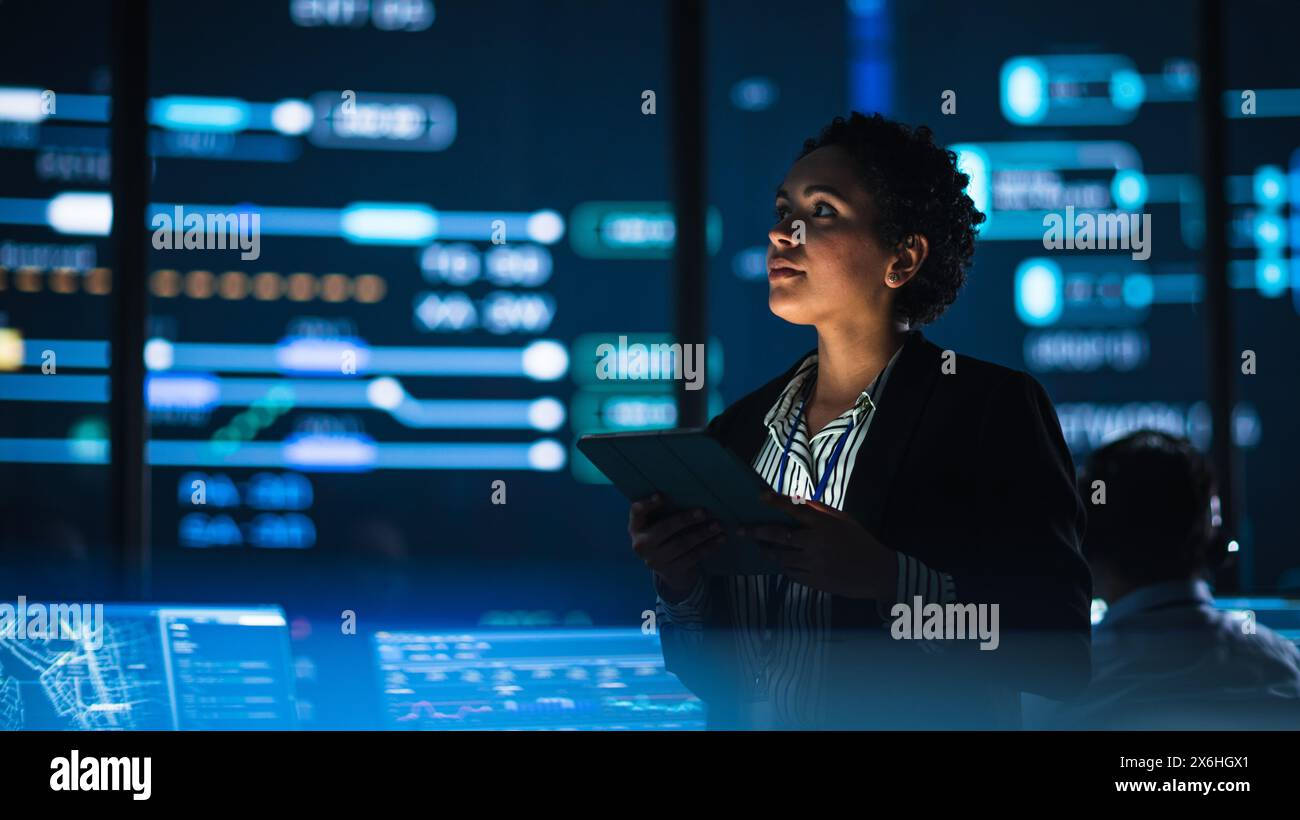Young Multiethnic Female Government Employee Uses Tablet Computer in System Control Monitoring ...