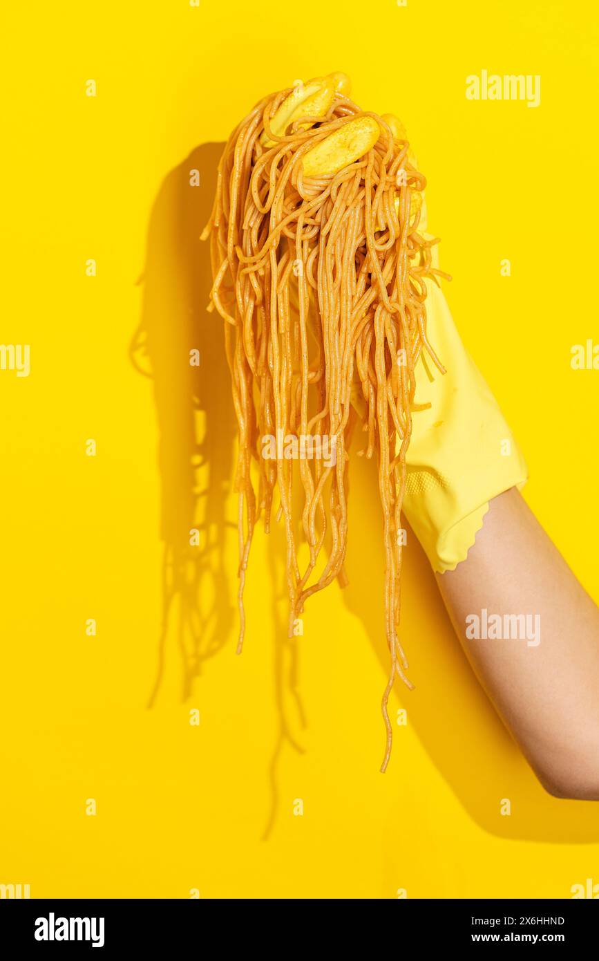 Hand holding cooked spagetti pasta on yellow background Stock Photo - Alamy