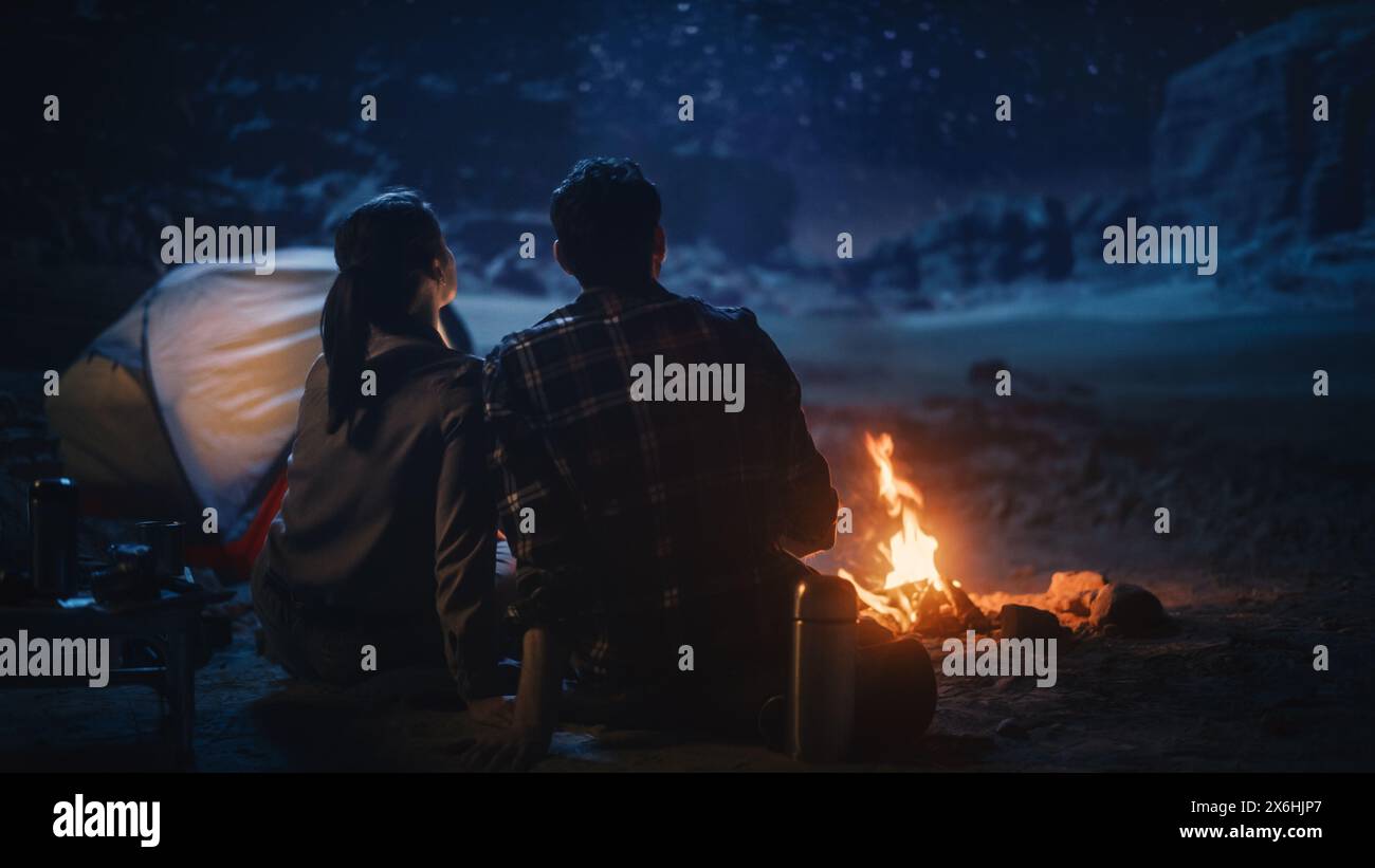 Happy Couple Tent Camping in the Canyon, Sitting by Campfire Watching Night Sky with Milky Way ...