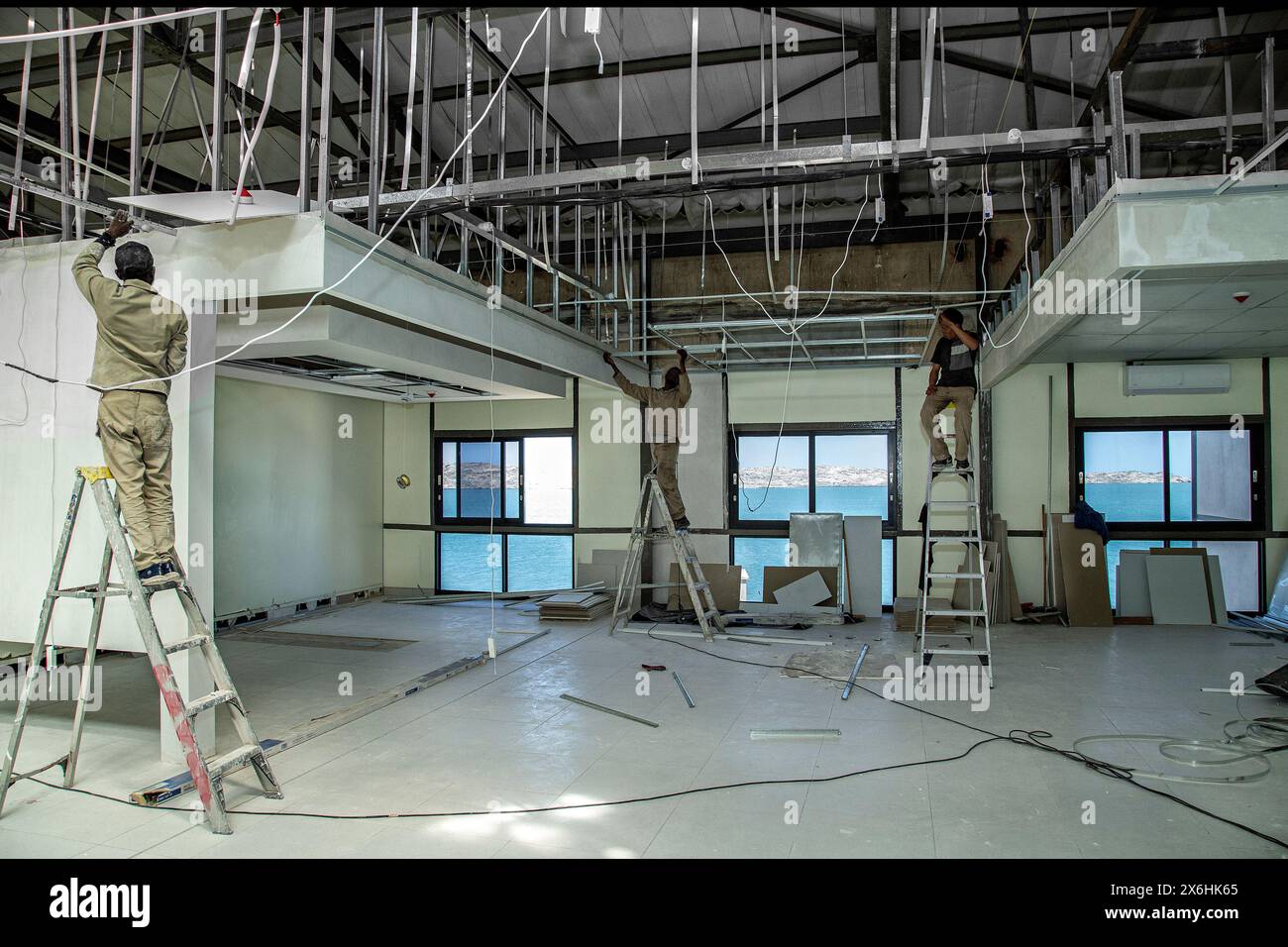 Three workers fitting a false ceiling in the old power station building ...