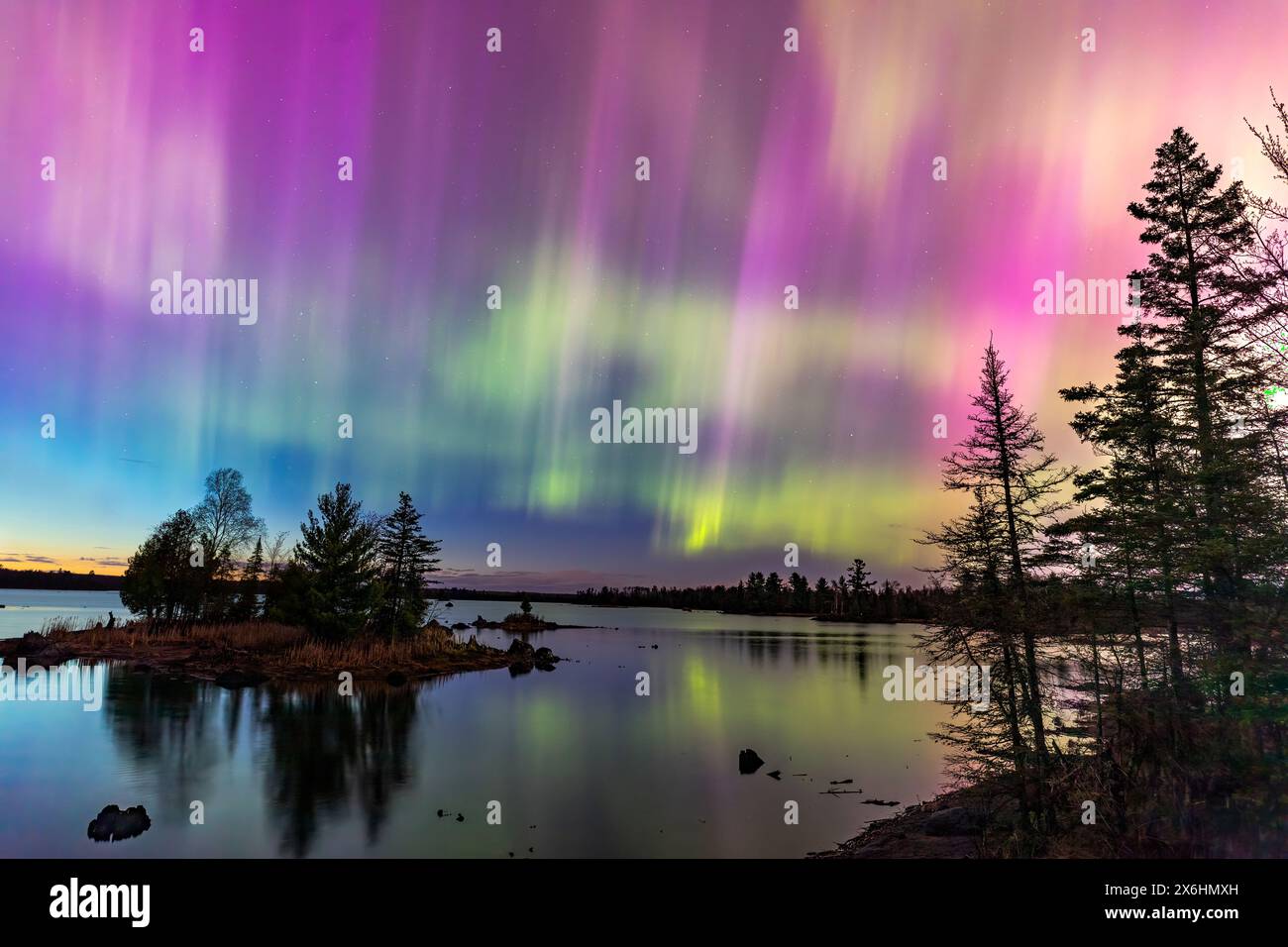 Northern lights erupt over a lake in Minnesota in a dark sky overhead ...