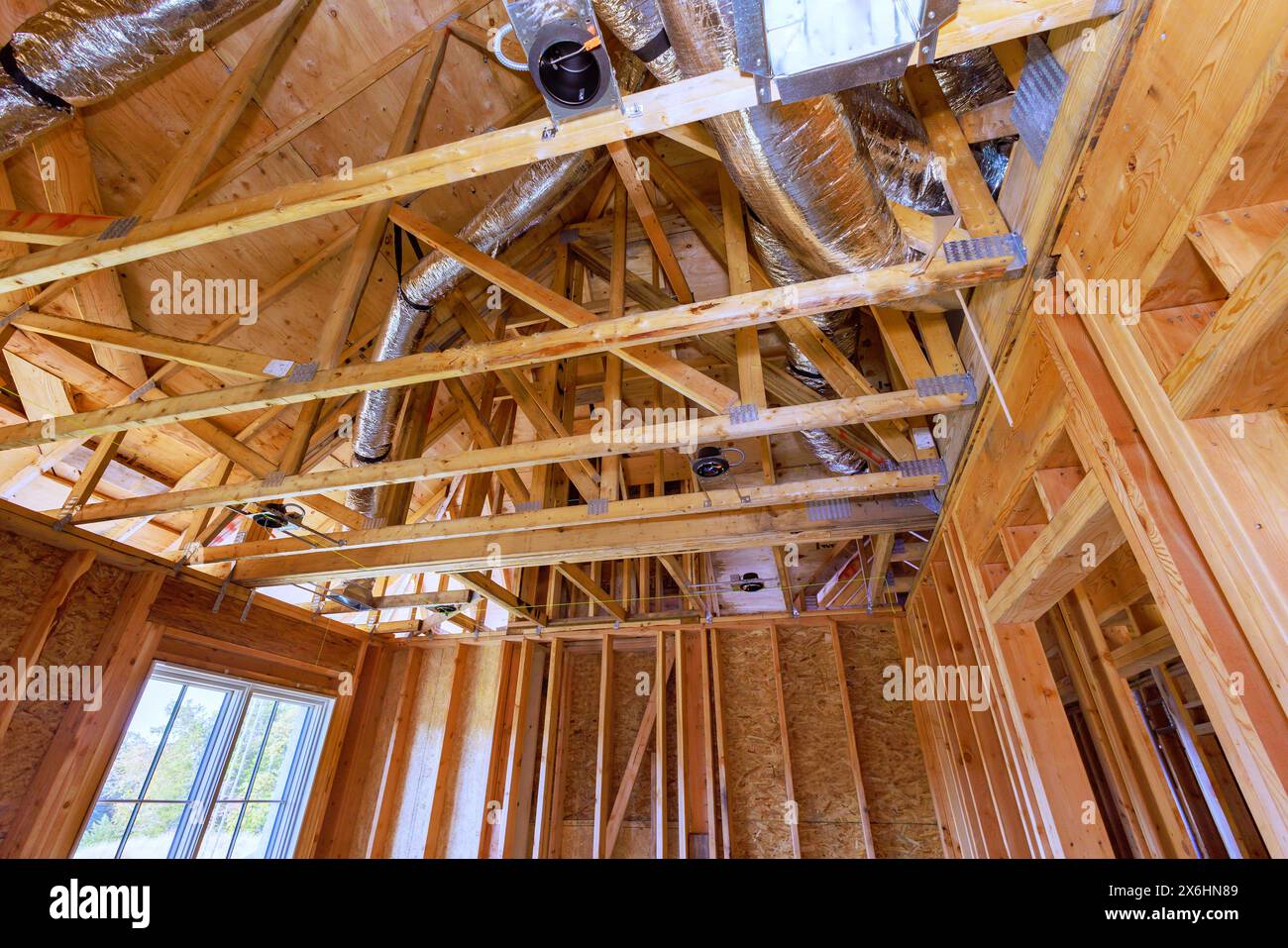 An unfinished wood frame for new residential project is being framed with wooden truss, post ...