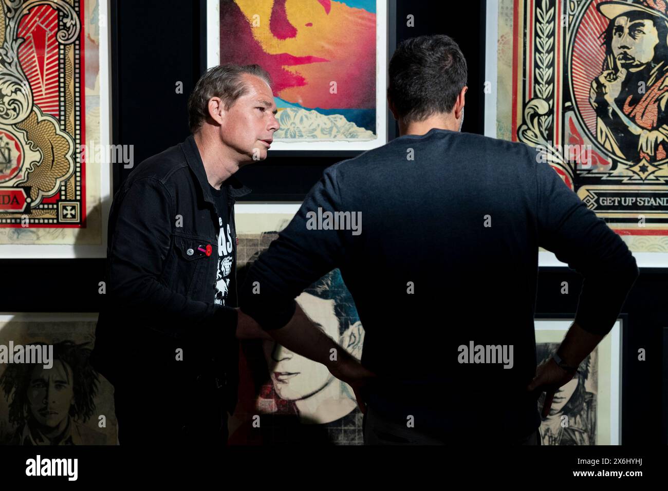 Shepard Fairey is talking with a visitor during the opening of the ...