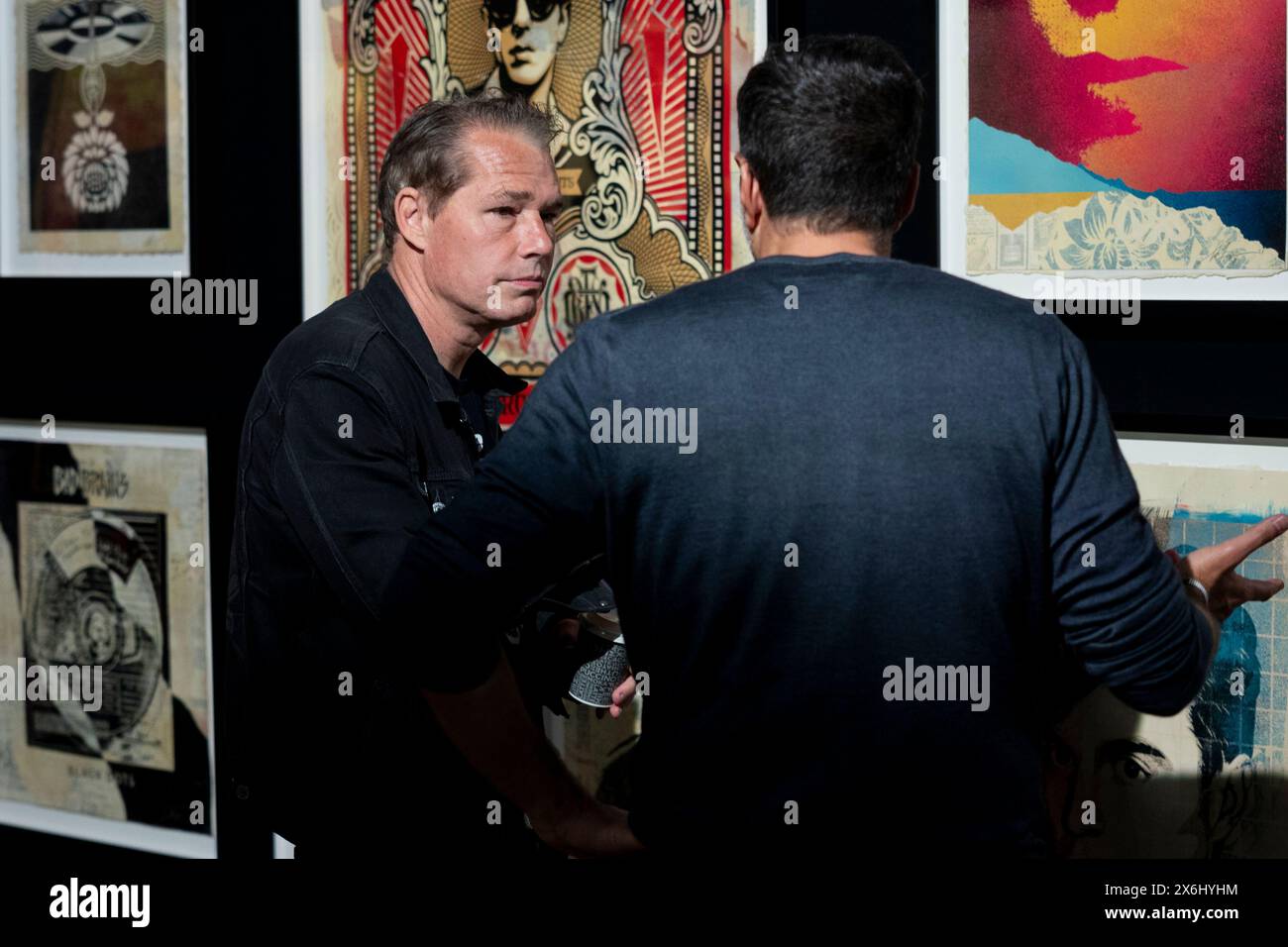 Shepard Fairey is talking with a visitor during the opening of the ...