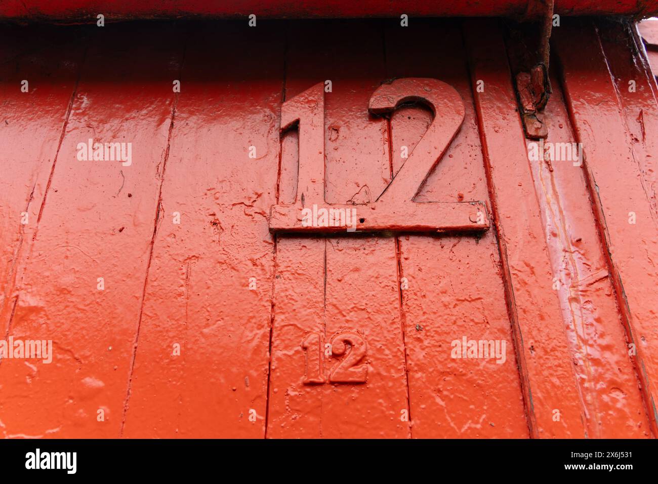 Red painted door number 12 Stock Photo - Alamy