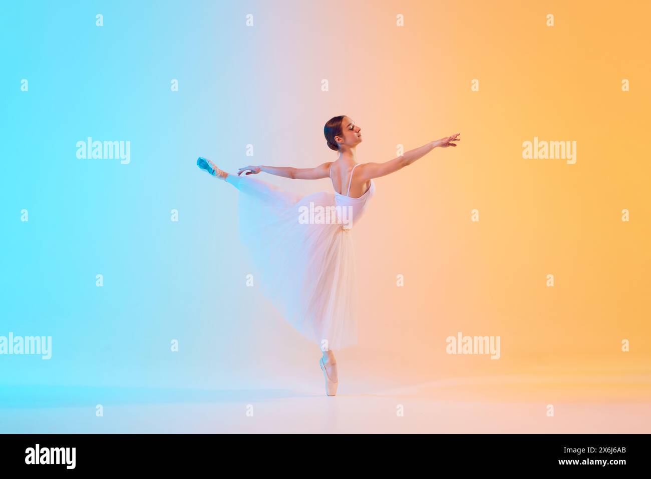 Elegant ballet dancer in white ensemble gracefully extends in neon ...