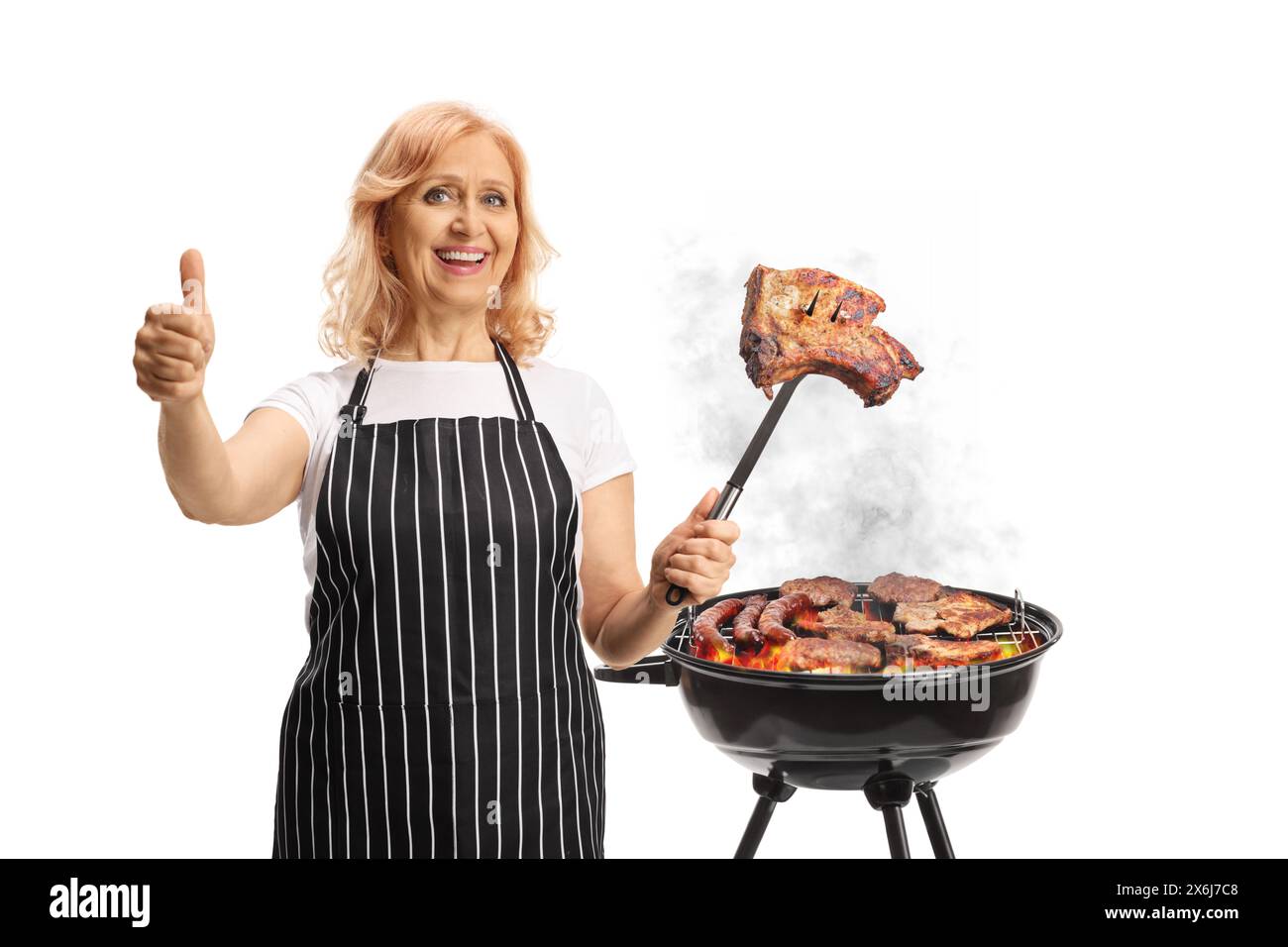 Woman grilling meat on a barbecue and gesturing thumbs up isolated on ...