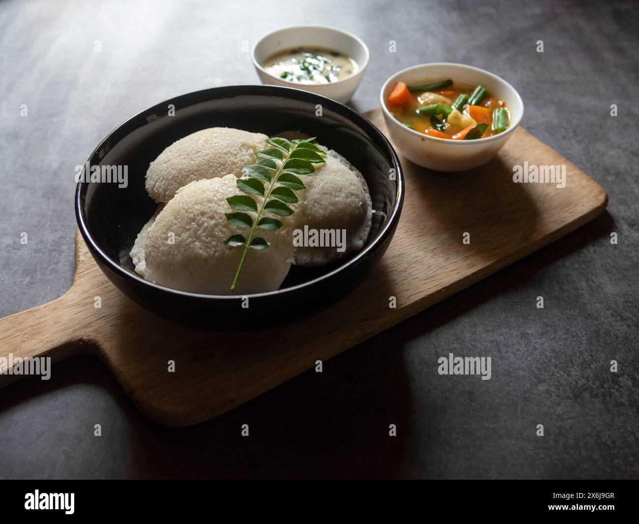 South Indian breakfast idli served in a bowl with condiments. Close up ...