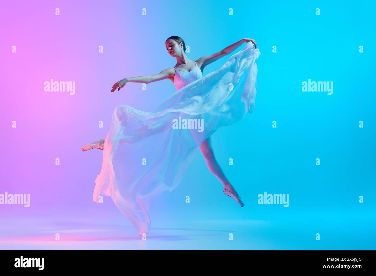Artistic ballerina dancing with white flowing fabric in action in neon ...