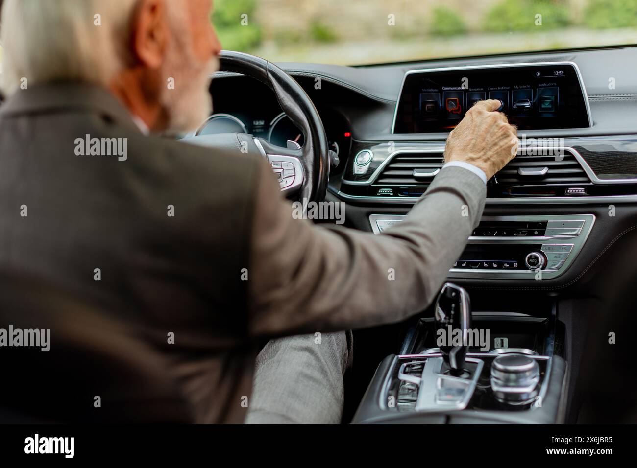 Mature man interacts with the cars touchscreen infotainment system ...