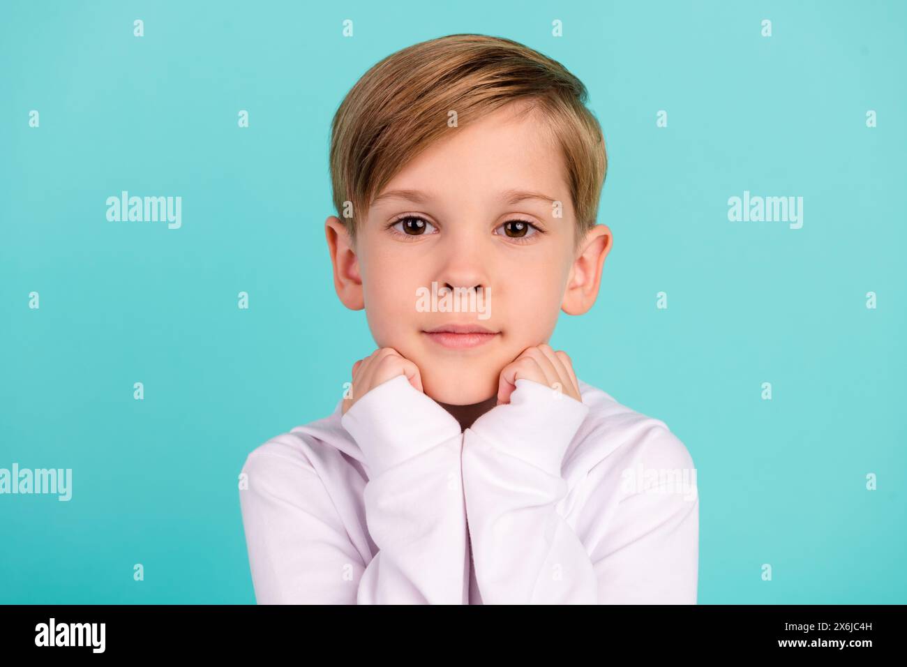 Portrait of lovely cute boy hands chin looking dreamy in camera ...